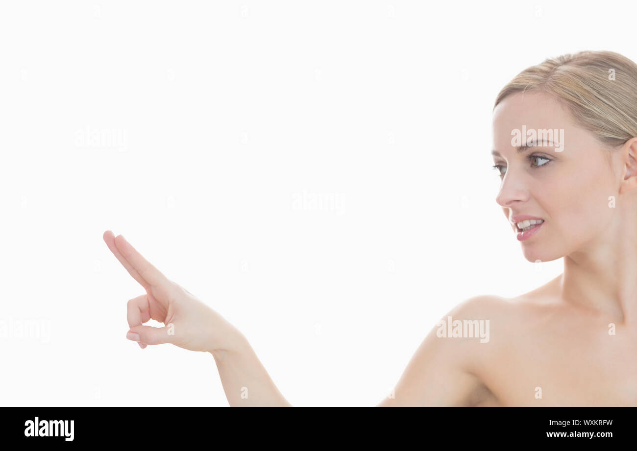 Beautiful young woman pointing at invisible screen against white ...