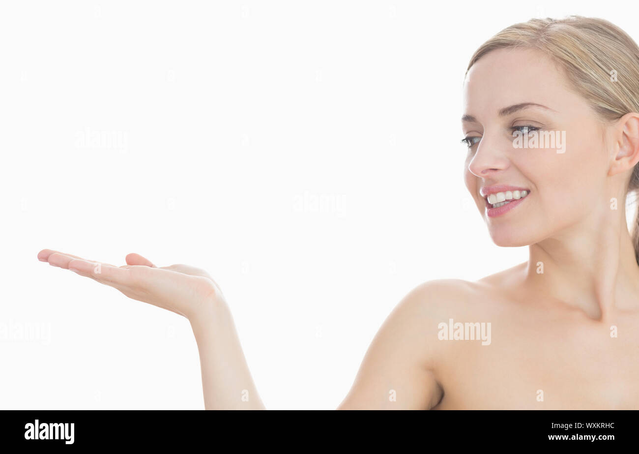 Beautiful young woman holding out open palm against white background ...