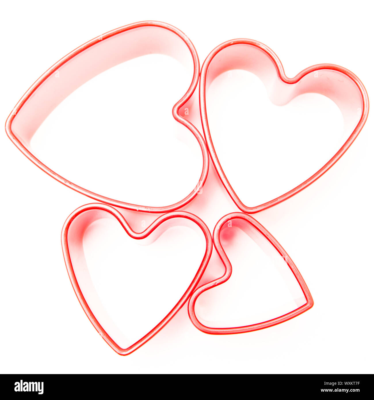 Four pink heart cookie cutters on white background Stock Photo - Alamy