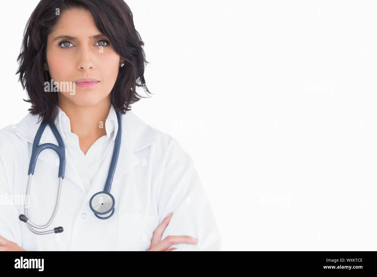 Pretty doctor with a stethoscope and arms crossed on white background ...