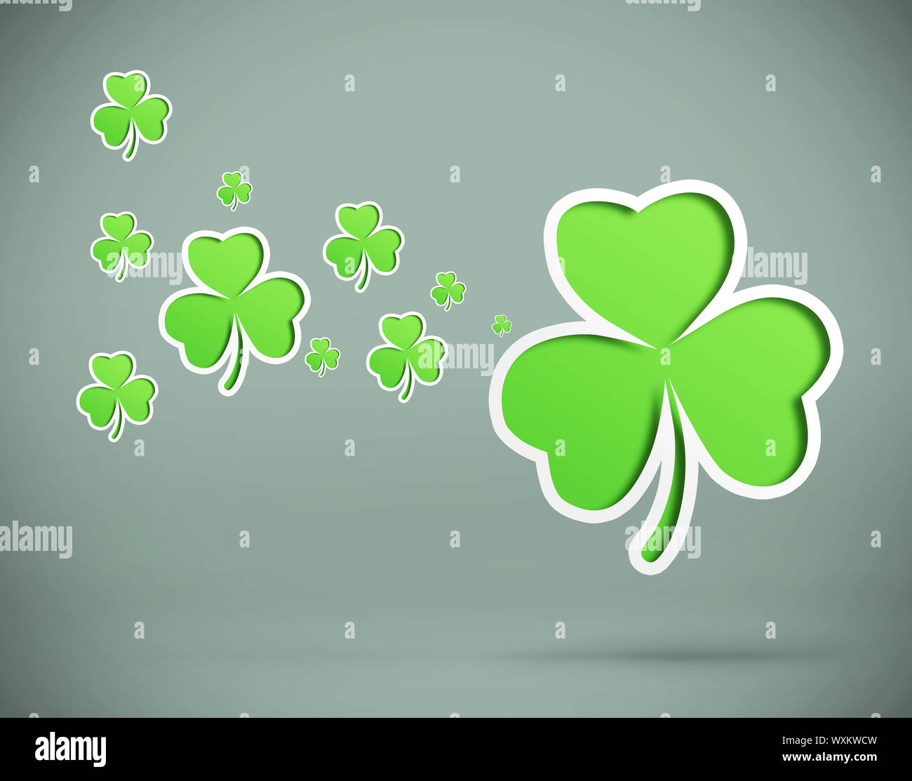 Different sized shamrocks on grey background Stock Photo - Alamy