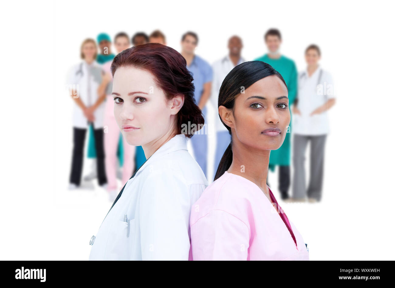 Serious doctor and nurse standing back to back with medical staff ...