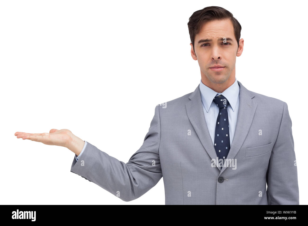 Serious businessman with open hand looking at the camera against white ...