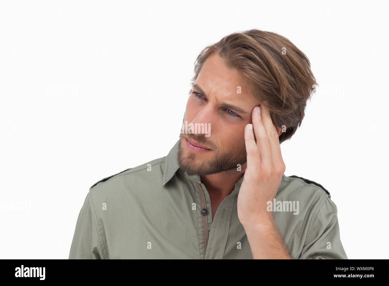 Man with headache looking away and touching his head on white ...