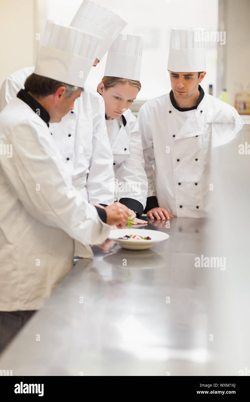 Trainees listening to the head chef in the kitchen at culinary school ...