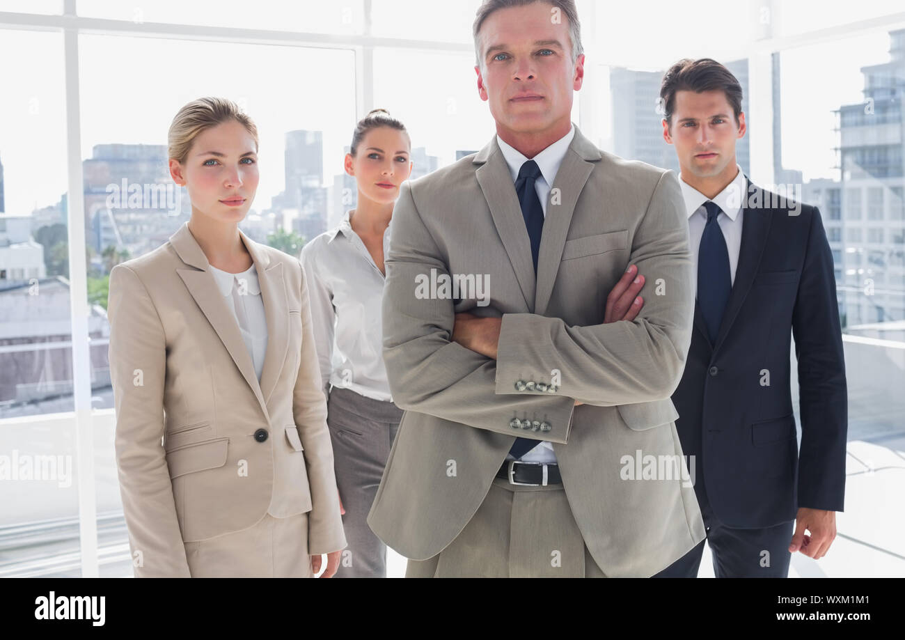 Boss standing with his arms folded with colleagues behind in their ...