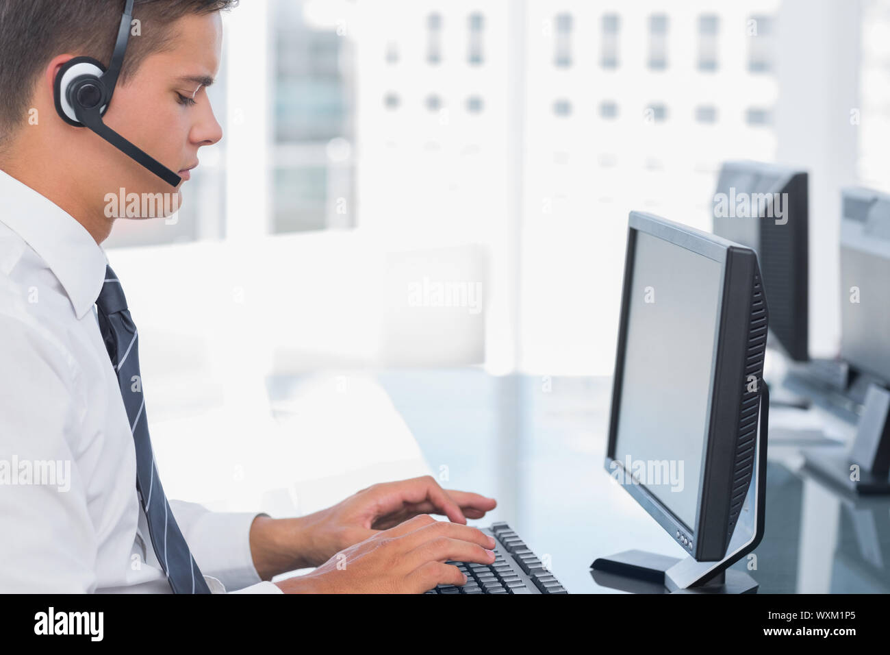Agent working in a call centre and using his computer Stock Photo - Alamy