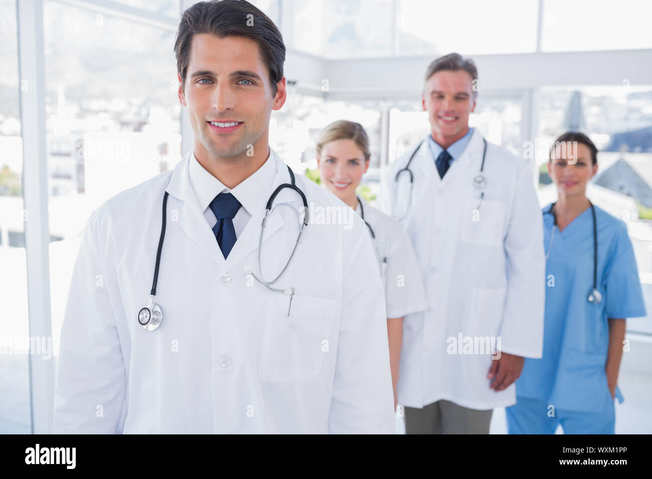 Attractive doctor standing in front of his team Stock Photo - Alamy