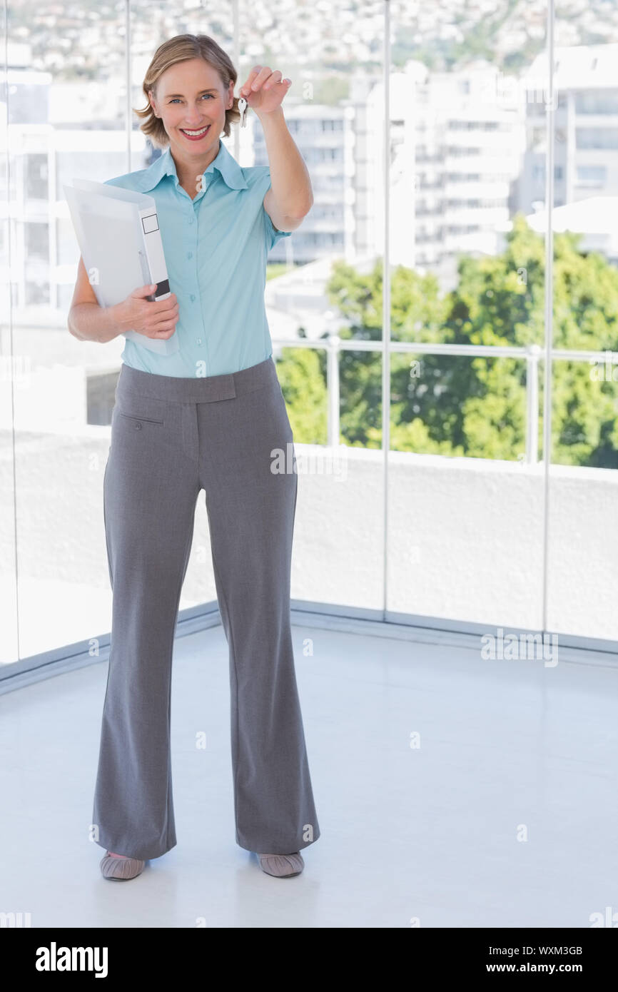 Happy estate agent showing house keys standing in office Stock Photo ...