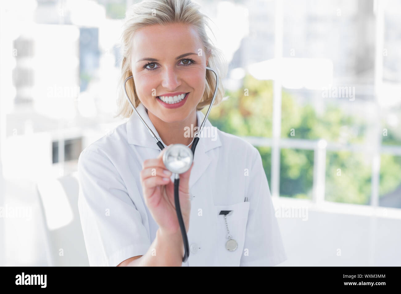 Radiant nurse showing her stethoscope at camera Stock Photo - Alamy