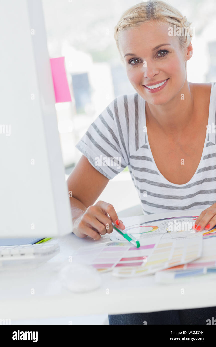 Pretty interior designer pointing at colour charts in front of a ...