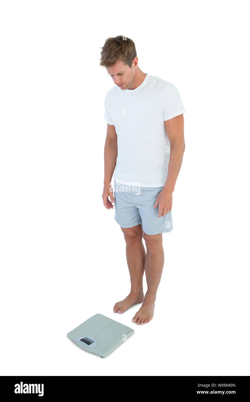 Athletic man looking at a weighing scale on white background Stock ...