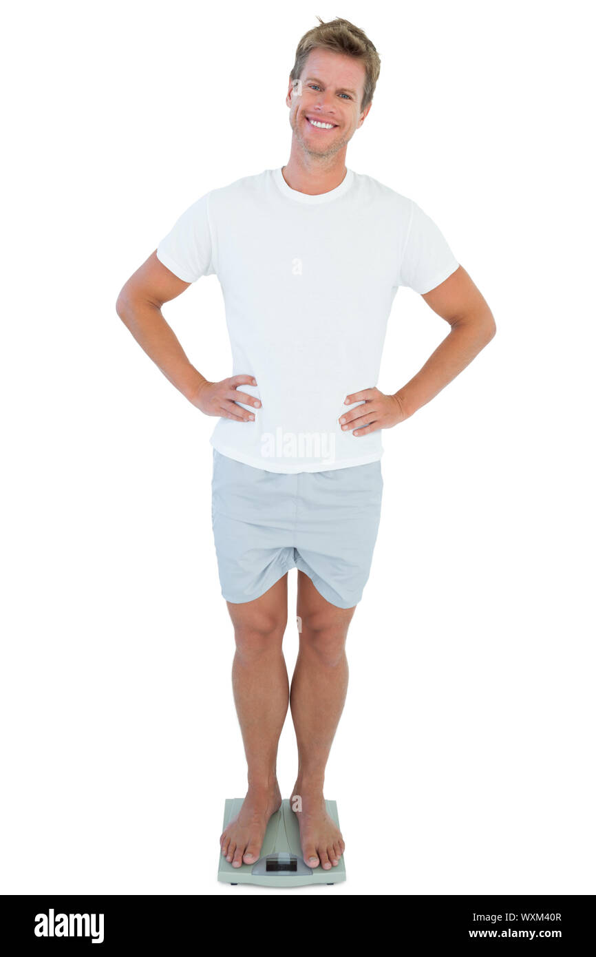 Cheerful man standing on a weighing scale on white background Stock ...