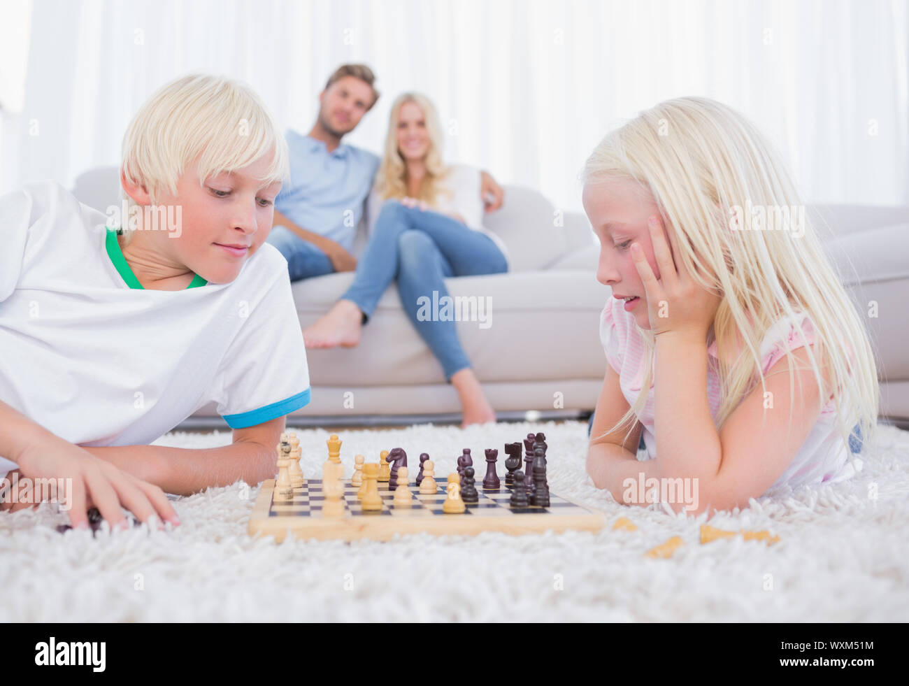 Cute siblings playing chess on the carpet Stock Photo - Alamy