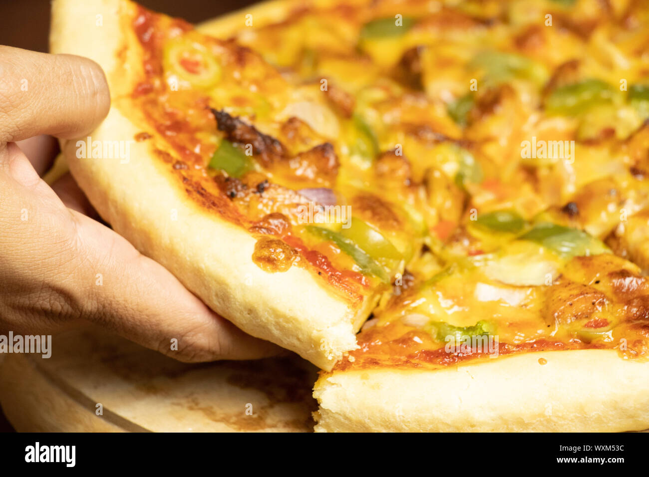 Pan Pizza slice take from hand side view with dark brown wood Stock ...
