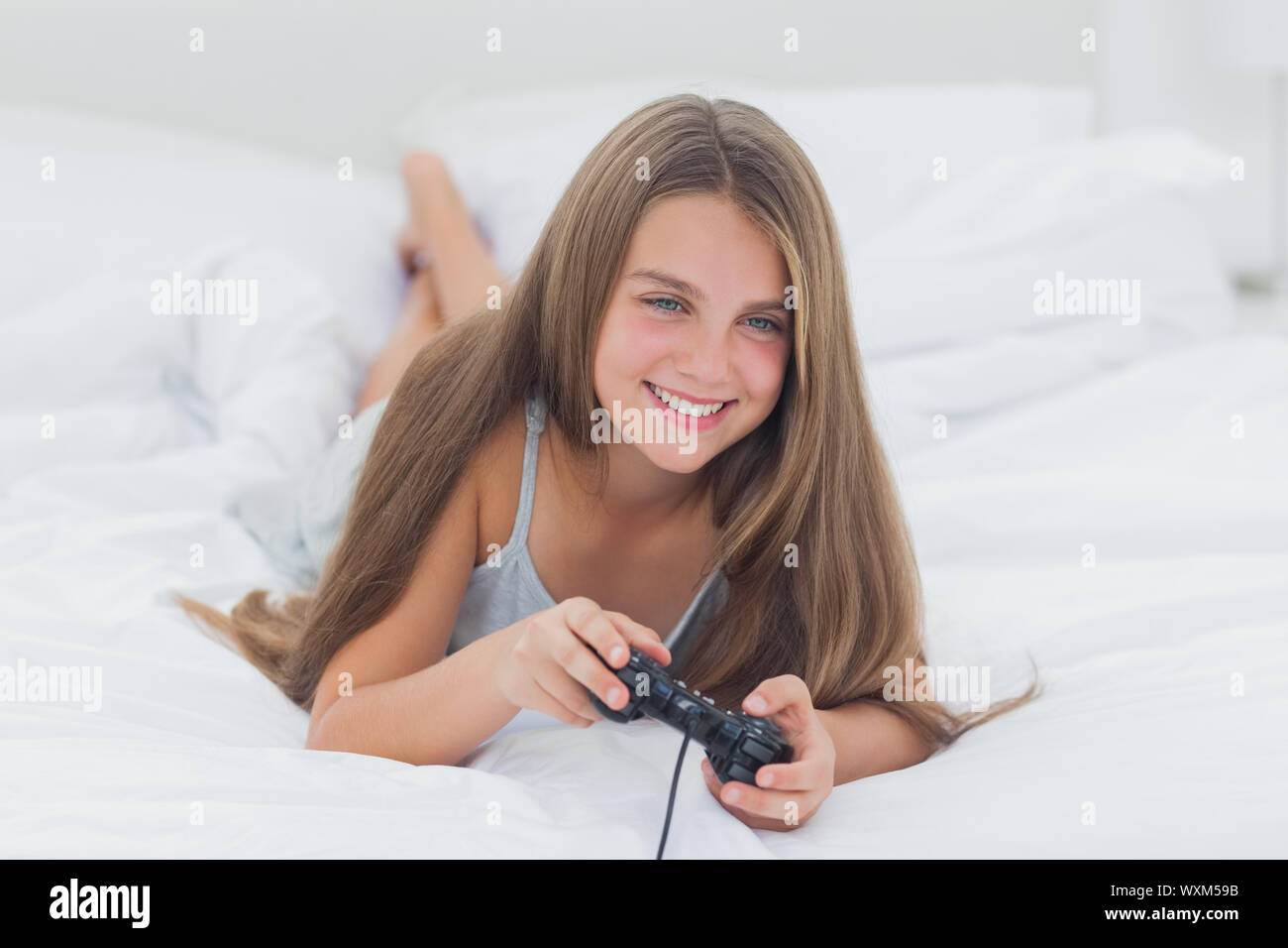 Cute girl playing video games while she is lying on her bed Stock Photo ...