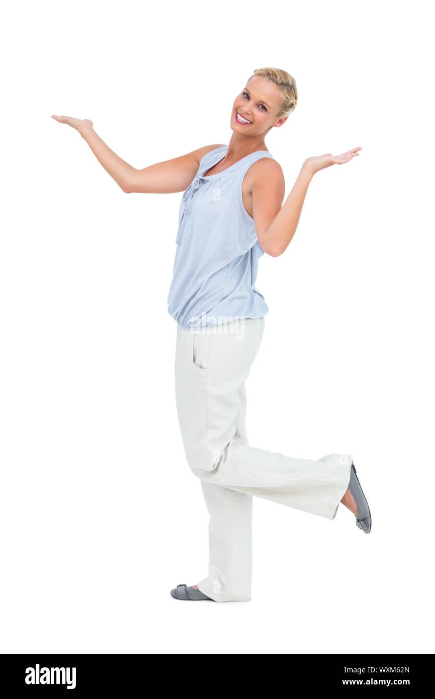 Happy woman standing with hands up and leg raised on white background ...