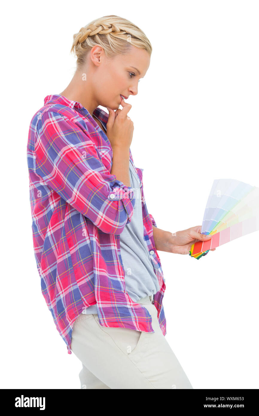 Concentrated young woman looking at color charts on white background ...