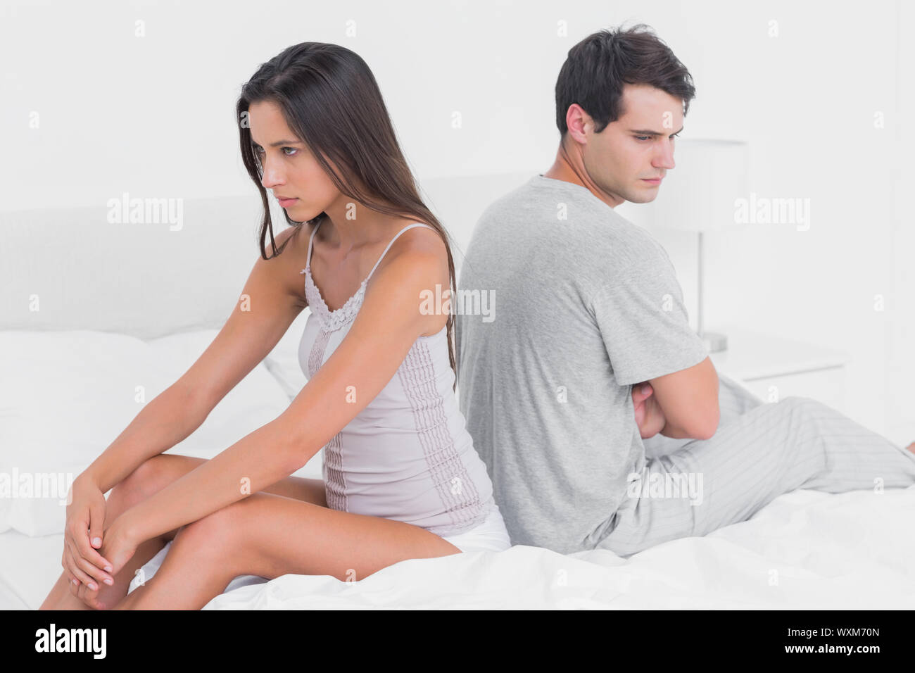 Sad Couple Ignoring Each Other Sitting Back To Back On Bed During A