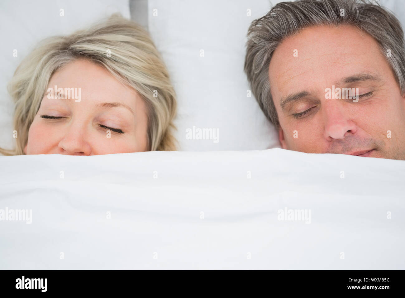 Couple sleeping under the covers at home in bed Stock Photo - Alamy