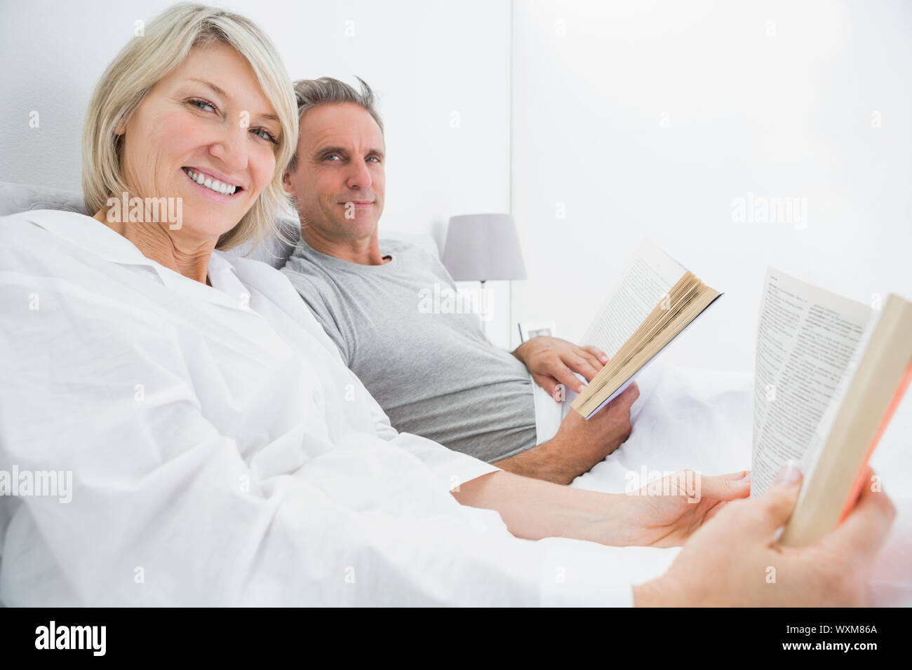 Happy couple reading books in bed at home in bedroom Stock Photo - Alamy