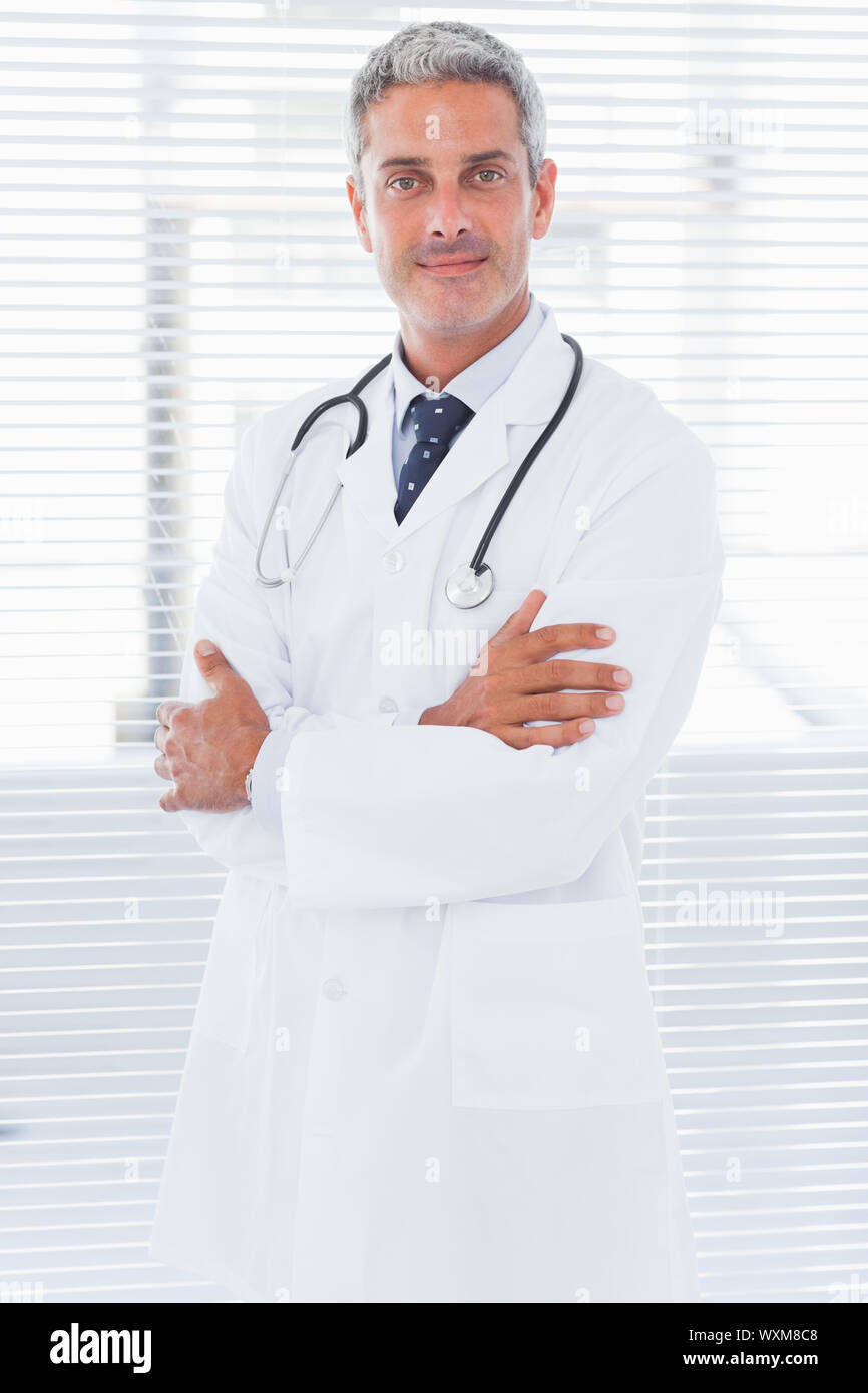 Happy doctor crossing his arms in medical office Stock Photo - Alamy