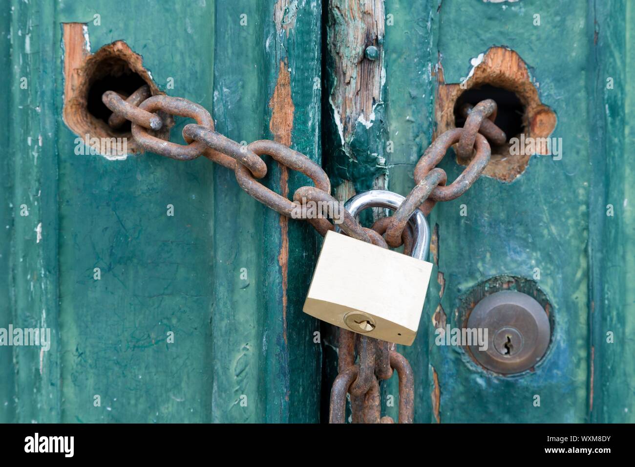 Padlock and chain on an old door, illustrating concepts of security and ...