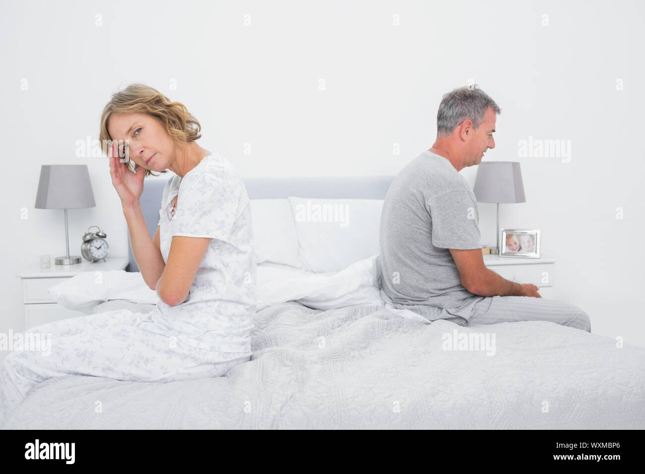 Annoyed Couple Sitting On Different Sides Of Bed Having A Dispute With