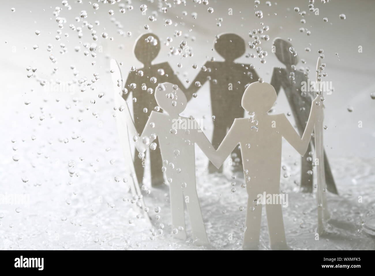 paper team linked together under rain weather concept Stock Photo - Alamy
