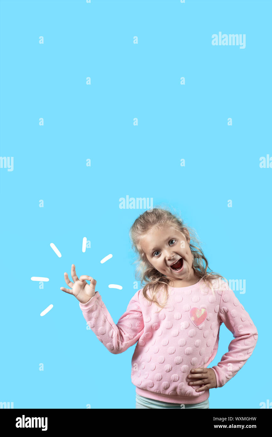 Cute cheerful girl with dimples and curly hair smiles and shows the OK ...