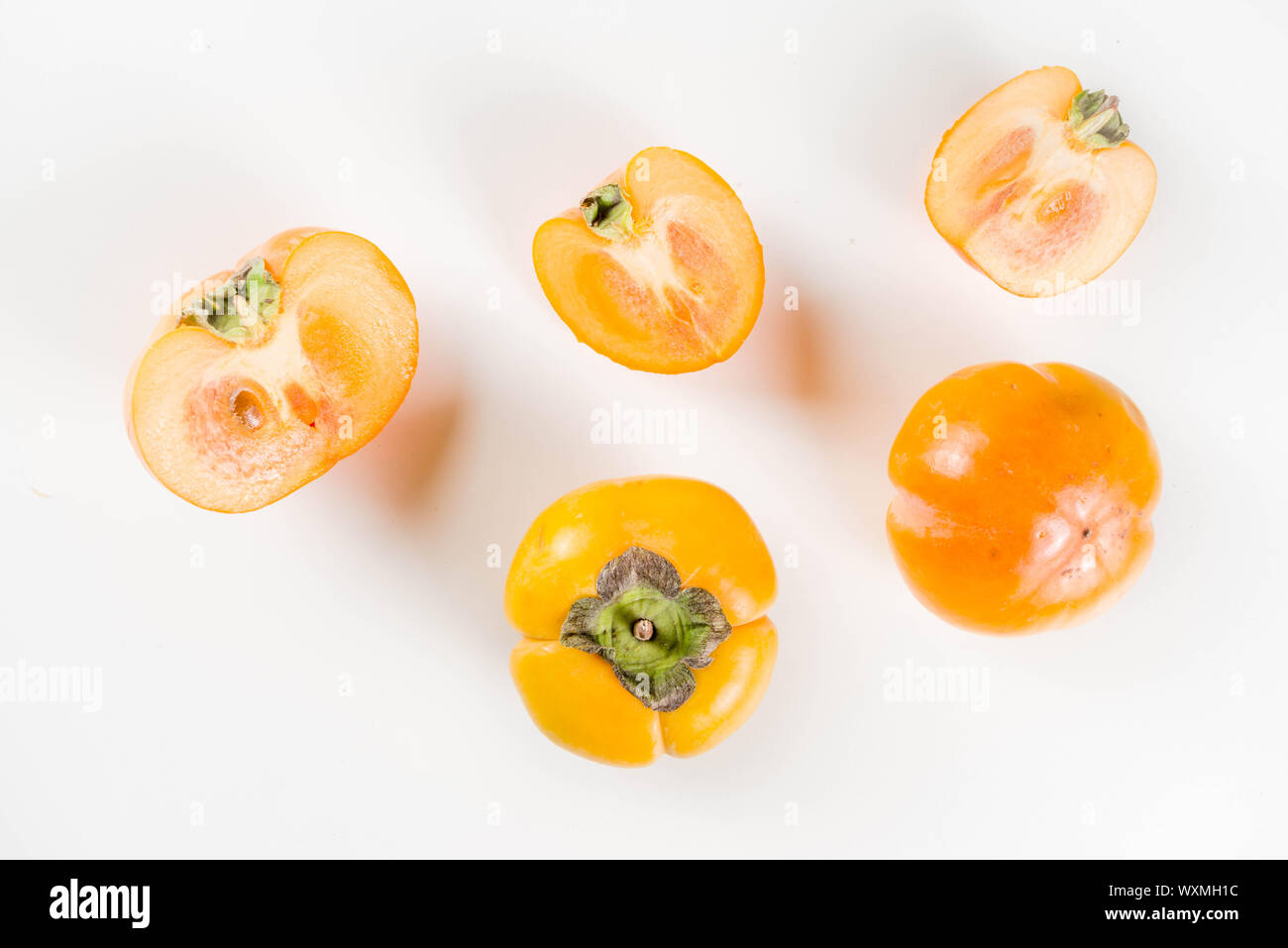 Whole and sliced persimmons, fresh organic farm fruit on a white ...