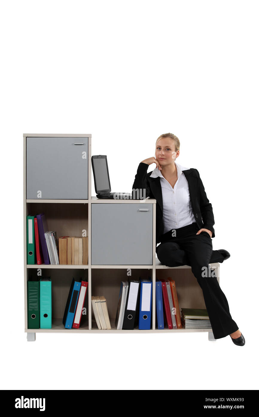 Woman sitting by modern bookcase Stock Photo - Alamy