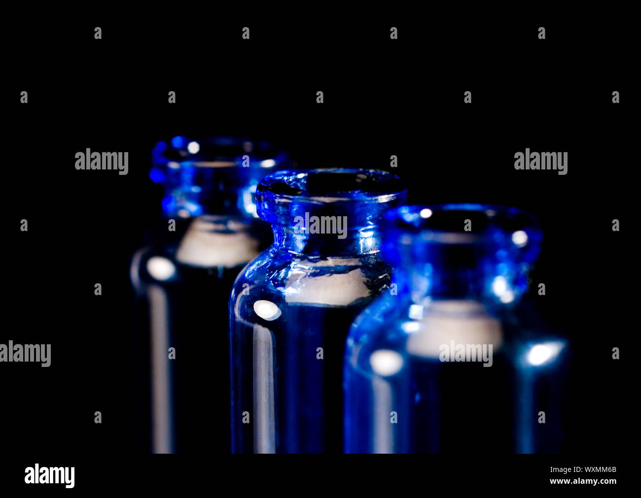 blue glass vials over black background backlit Stock Photo - Alamy