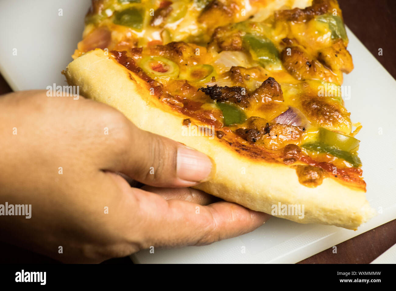 Pan Pizza slice take from hand side view with dark brown wood Stock ...