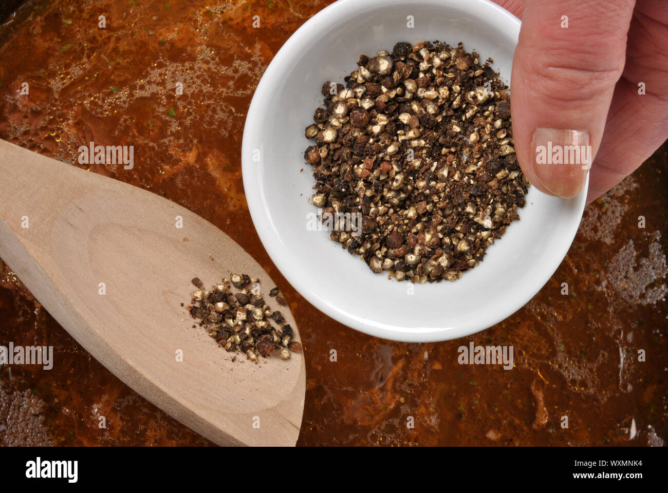 add some organic black pepper into a sauce Stock Photo - Alamy