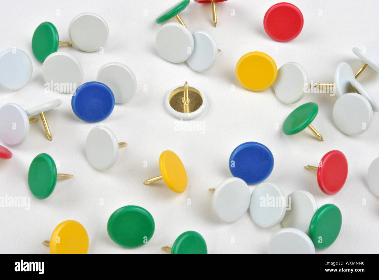 some coloured office pins and a white background Stock Photo - Alamy