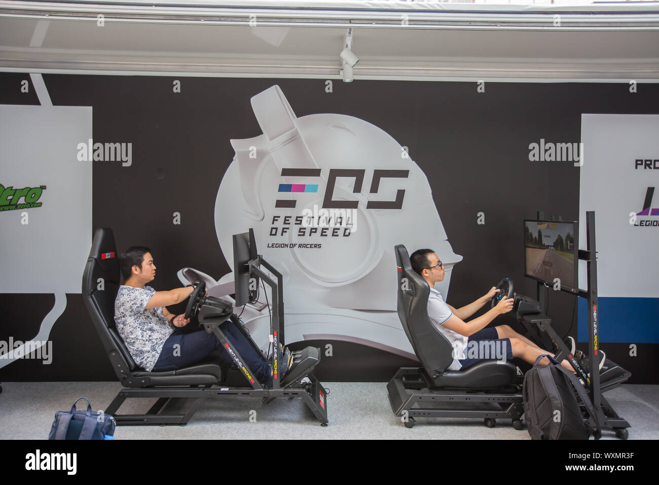 2 men driving on a car simulator during the Singapore Grand Prix season ...