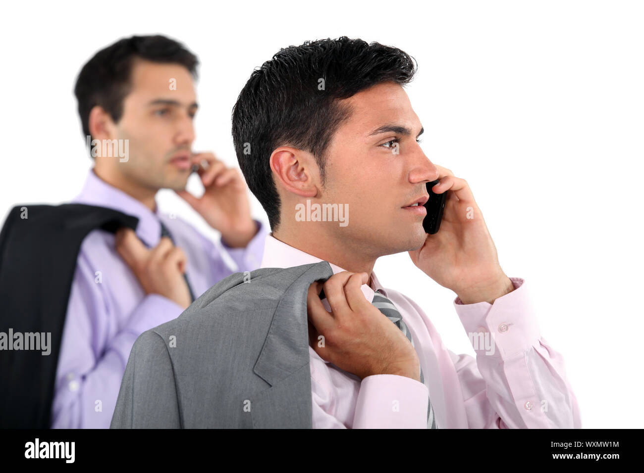 Two businessmen with jackets over shoulders making phone calls Stock ...