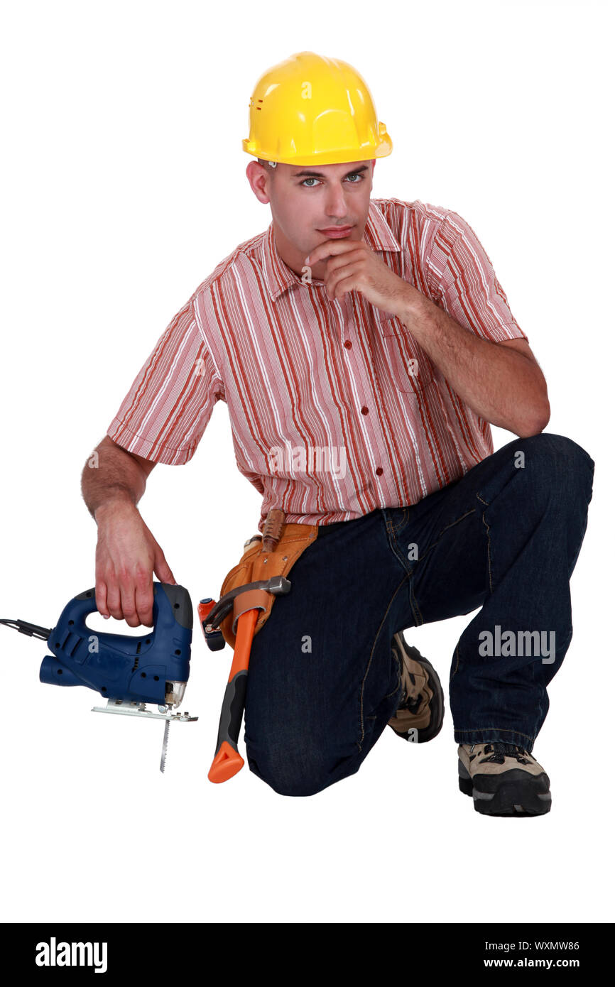 Confident worker kneeling with band saw Stock Photo - Alamy