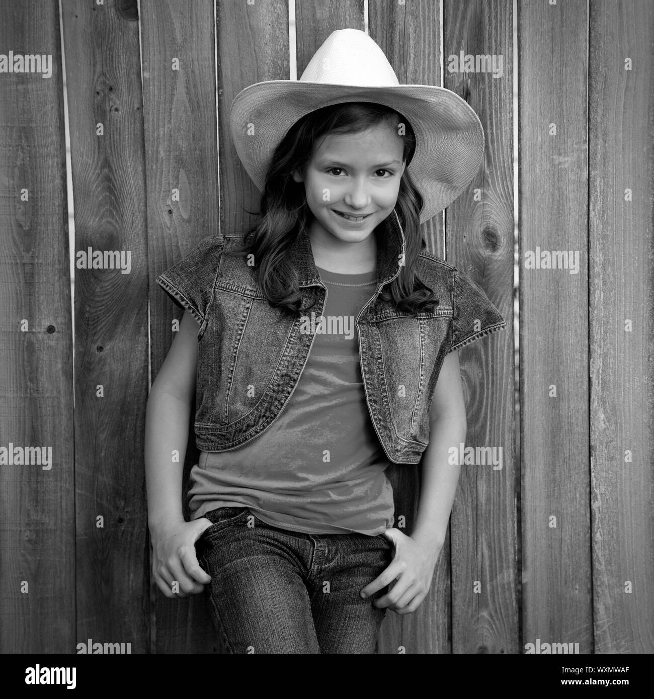 Children girl as kid cowboy girl cowgirl posing on wooden fence far ...