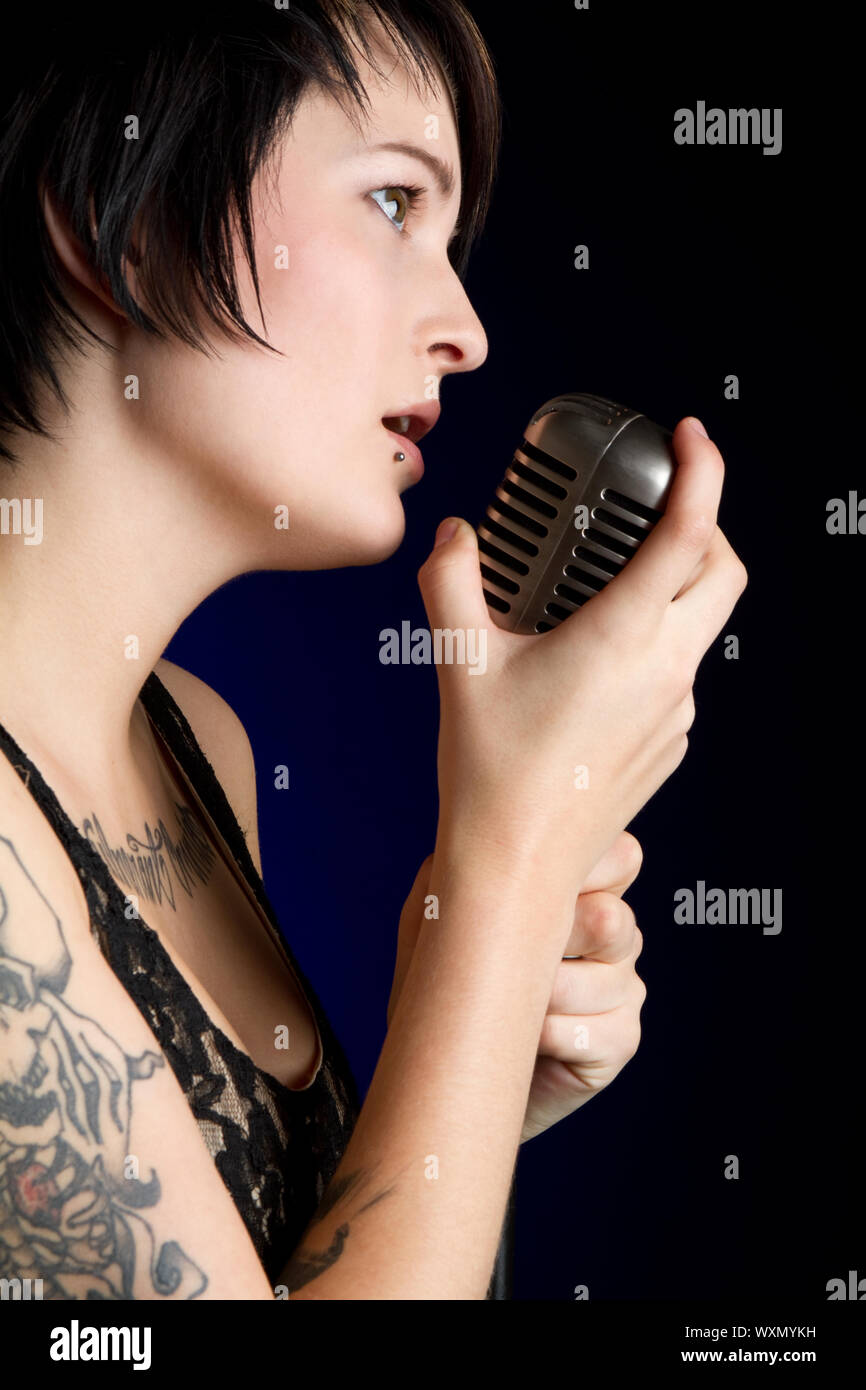 Pretty girl singing into microphone Stock Photo - Alamy