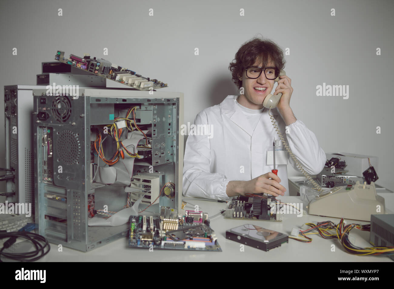 Happy computer technician in his laboratory is talking on the phone ...