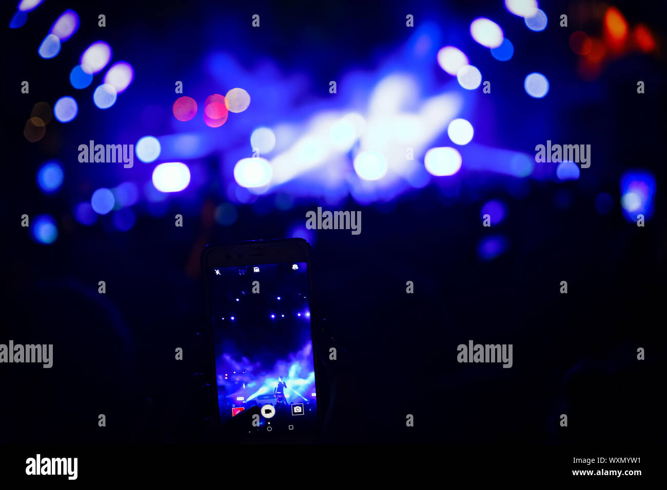 People taking photographs with touch smart phone during a music ...