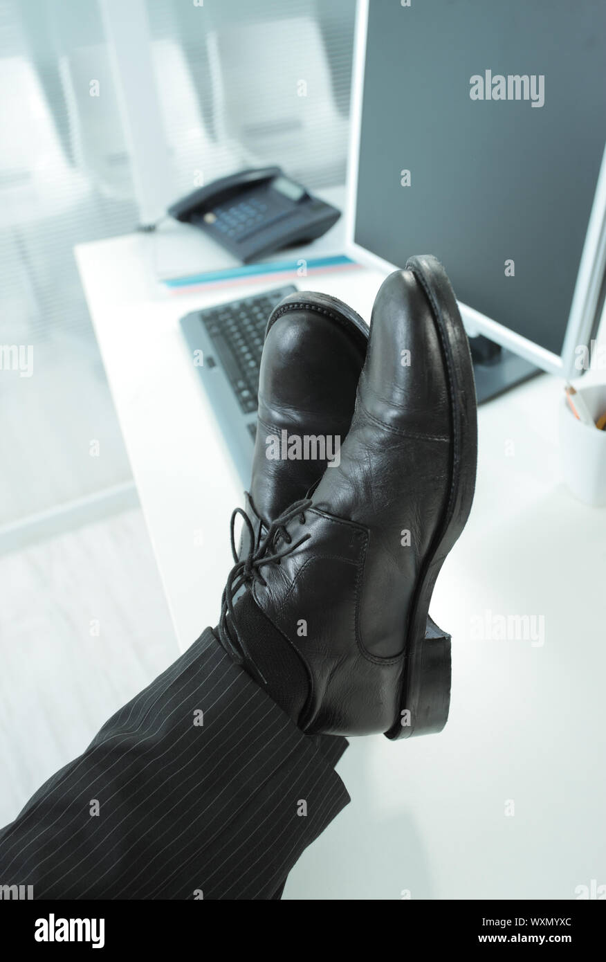 Cropped shot of a manager in office with feet on desk Stock Photo - Alamy