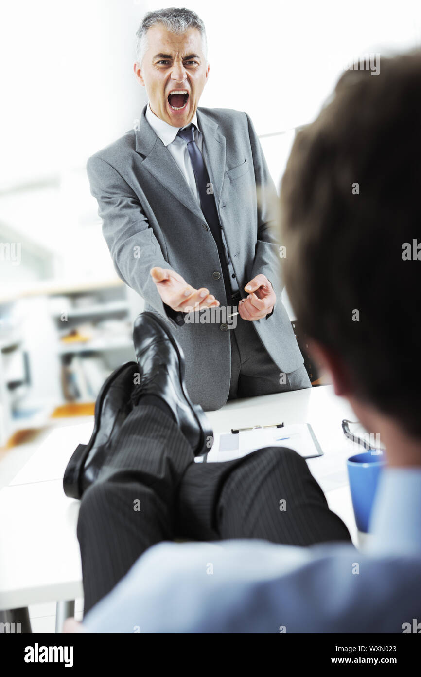 Business man relaxing at desk while his boss shouting angry Stock Photo ...