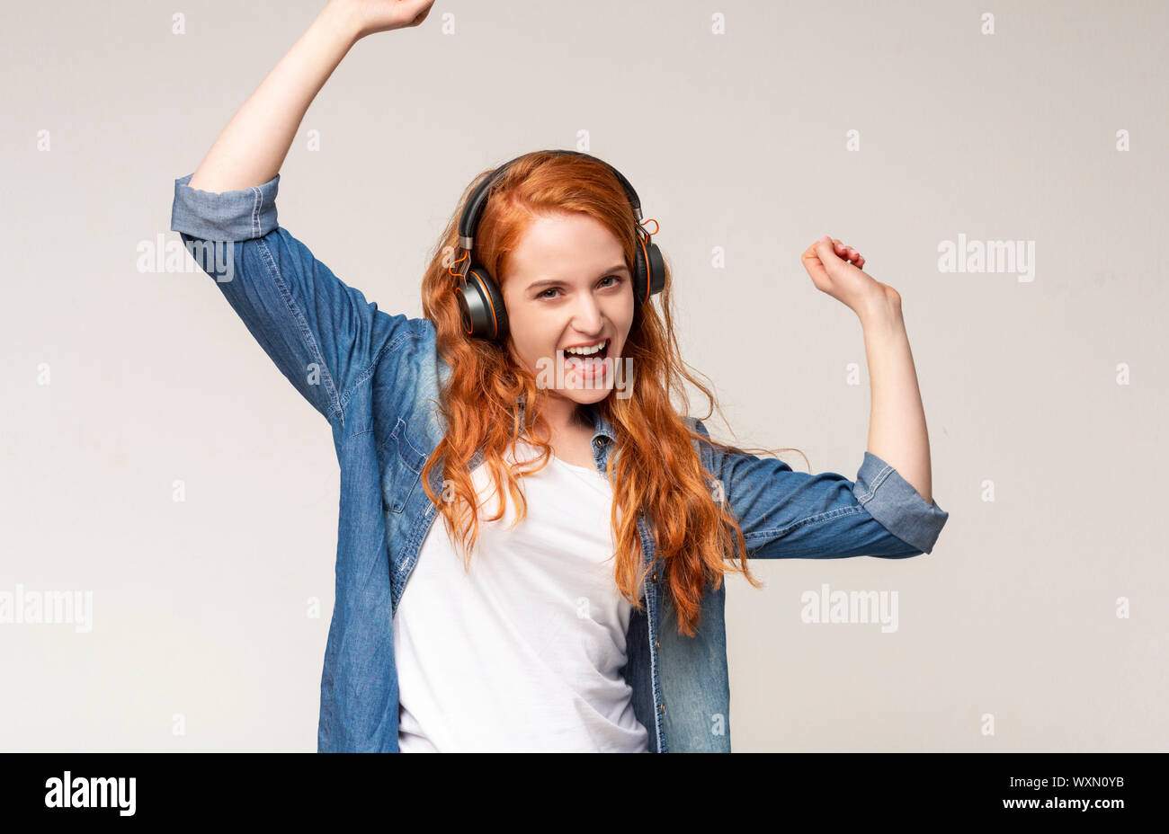 Happy ginger girl in headphones listening to music and dancing Stock ...