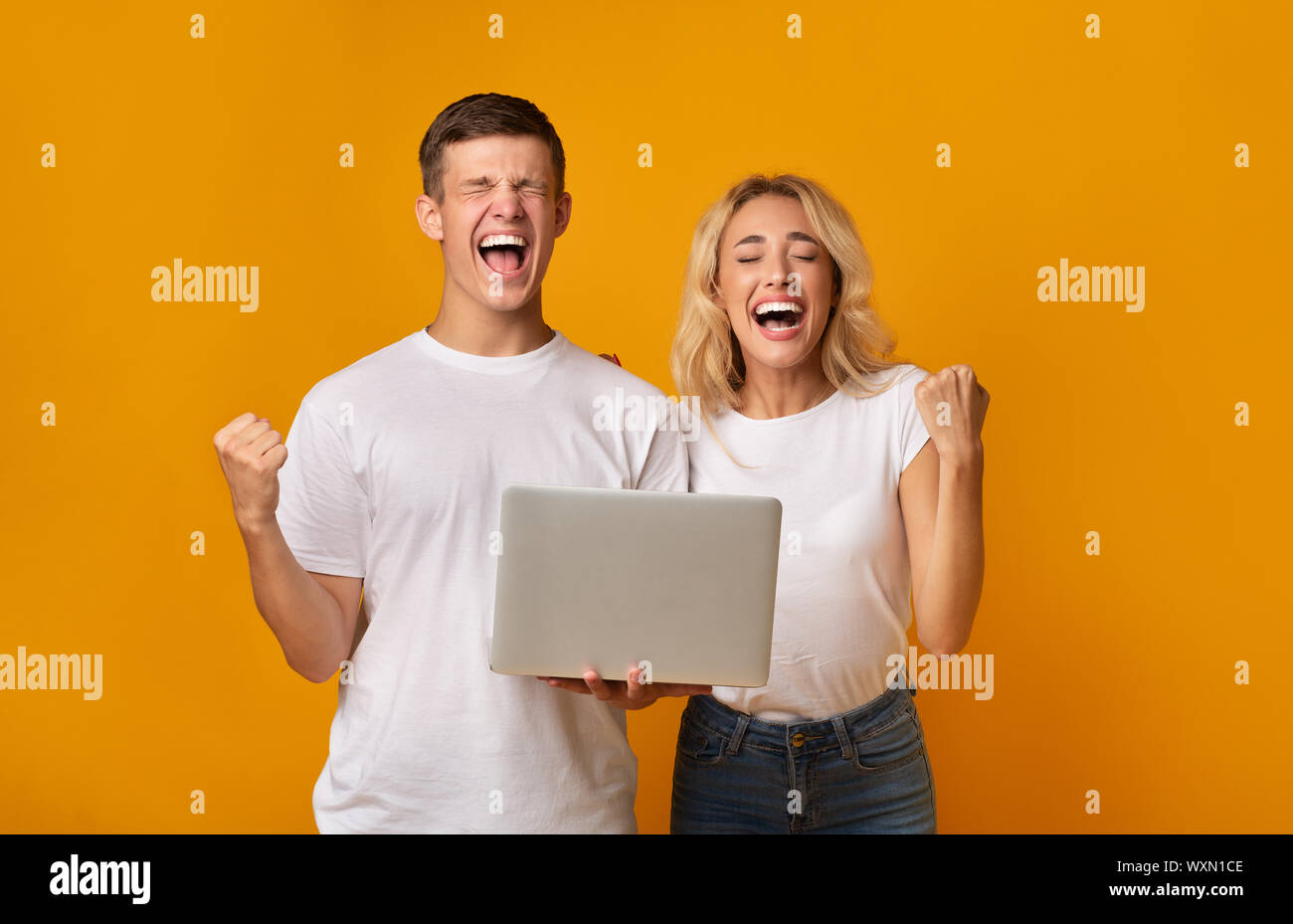 Excited young couple celebrating win with laptop Stock Photo - Alamy
