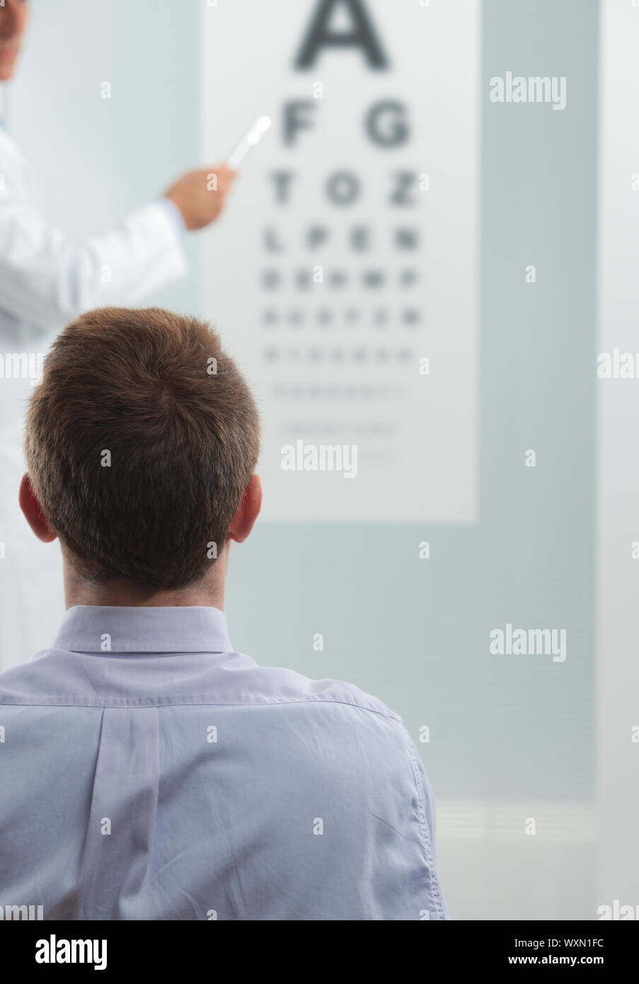 Optometrist and patient, doctor pointing at eye chart Stock Photo - Alamy