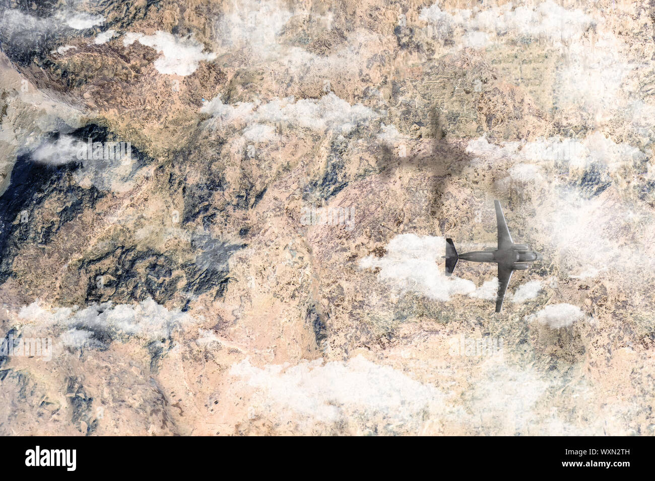 Plane flies above mountains in clouds and throws a shadow on earth. Top ...