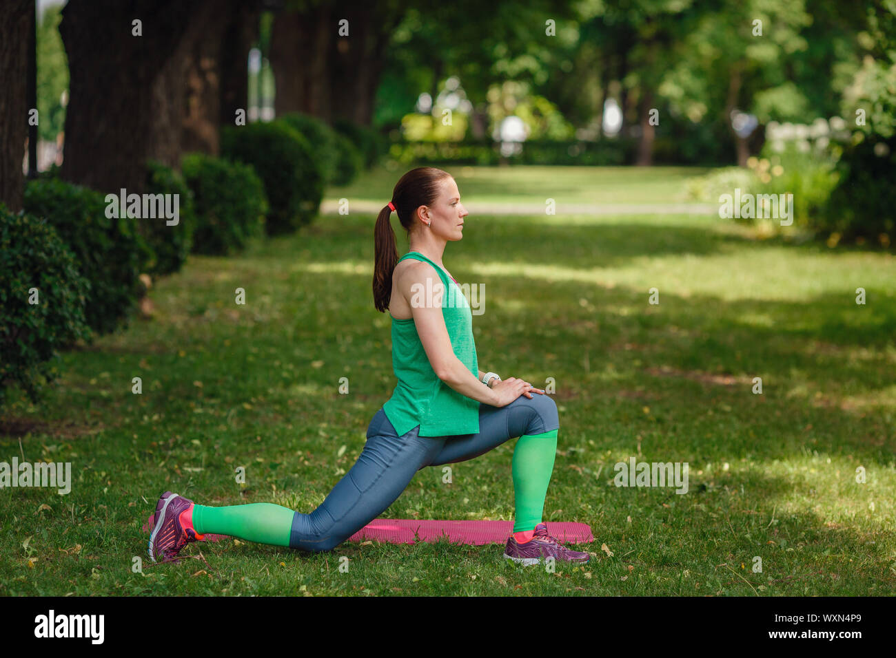 Young fitness woman runner stretching and warming up legs before run. The idea and concept of a ...